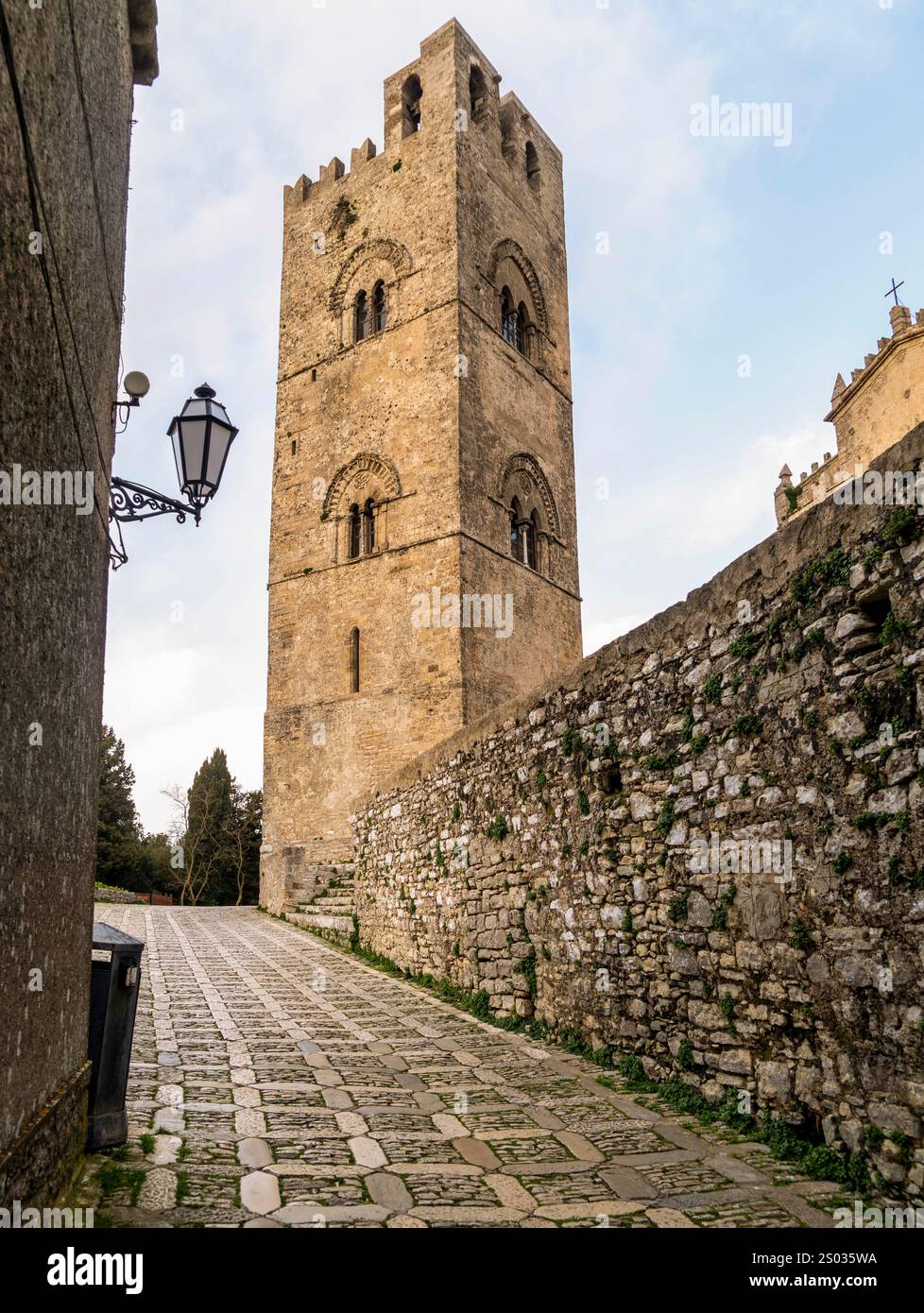A historic stone tower stands tall beside a cobblestone path, flanked ...