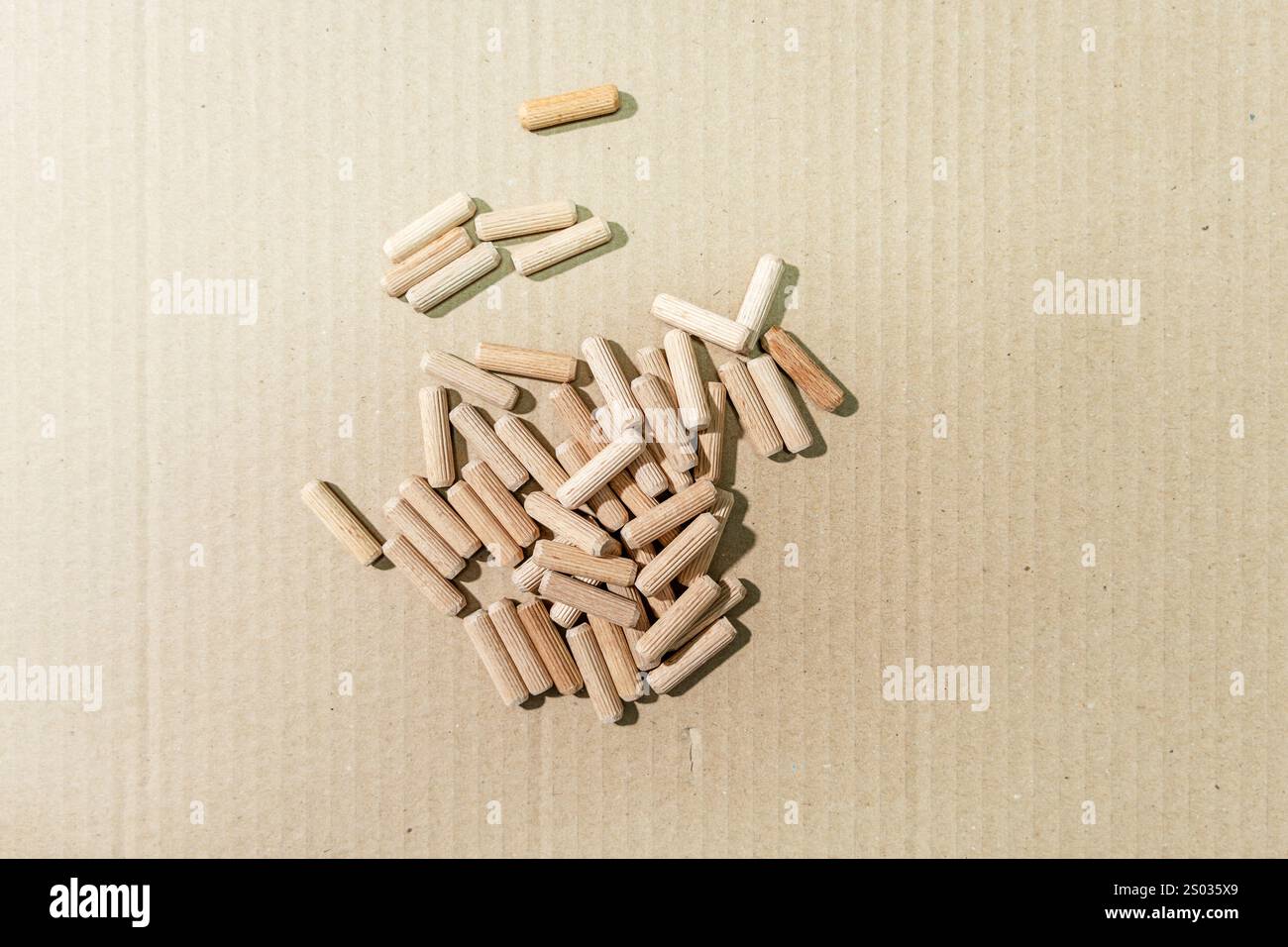 Wooden dowels for furniture assembly lie on a cardboard surface ...