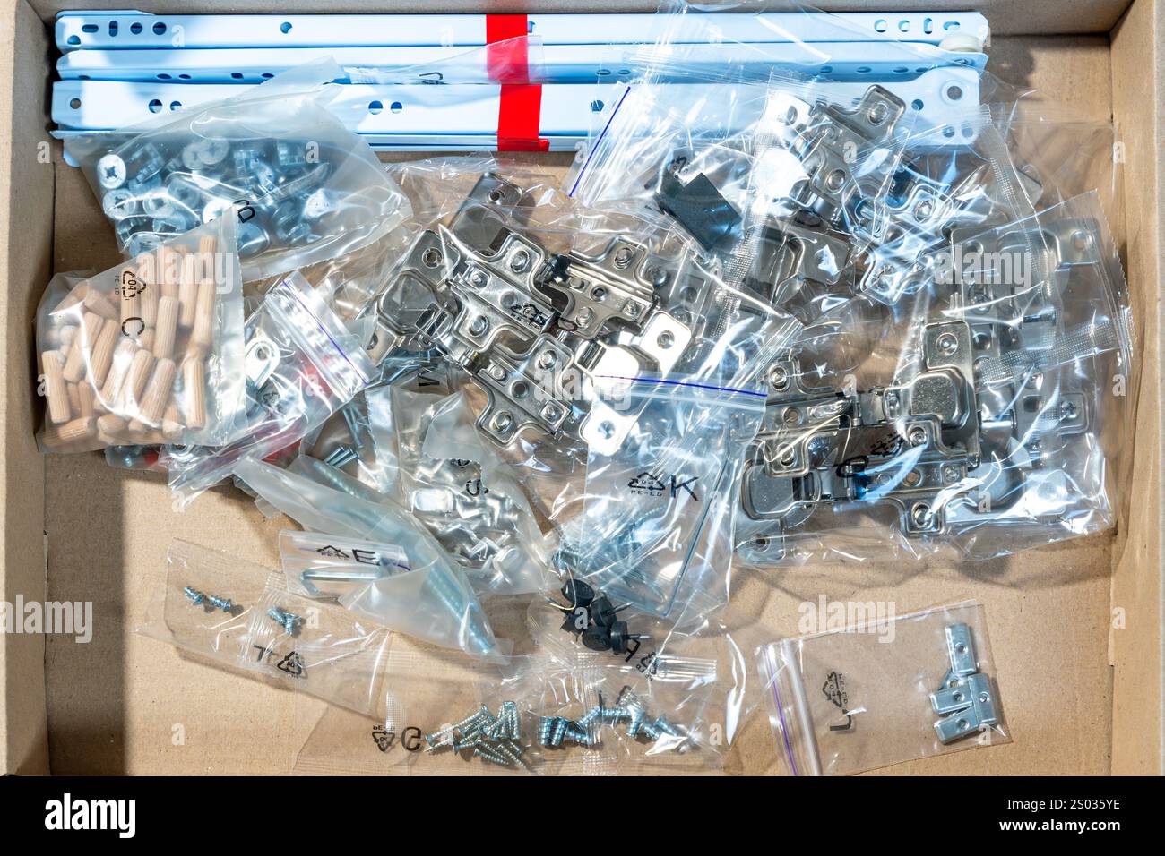 Cardboard box with furniture assembly kit. Screws, wooden dowels, door ...