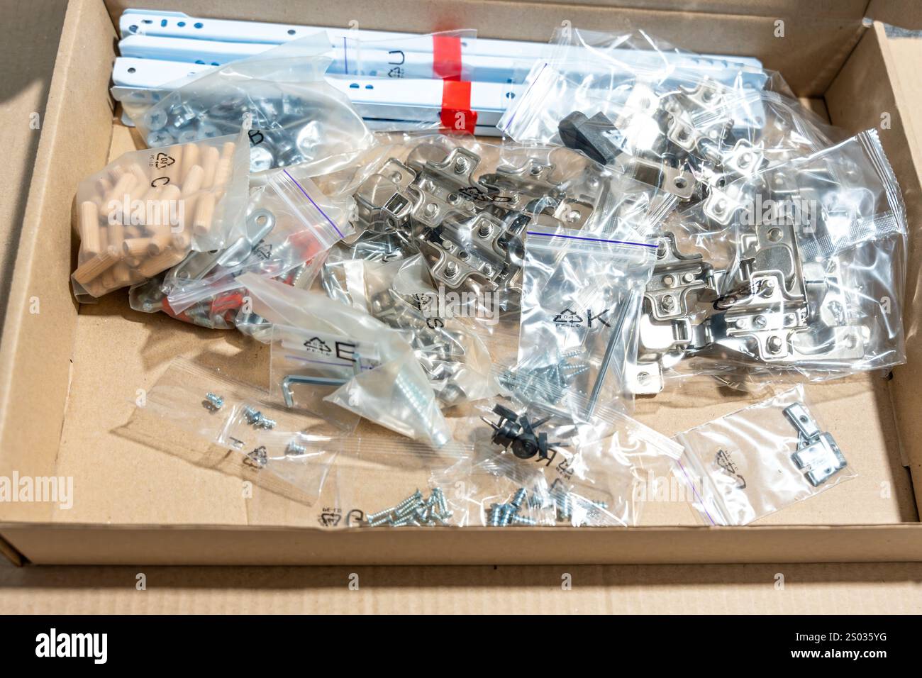 Cardboard box with furniture assembly kit. Screws, wooden dowels, door ...