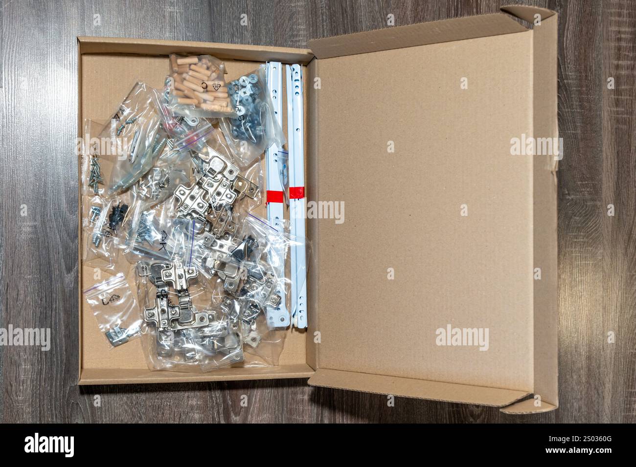 Cardboard box with furniture assembly kit. Screws, wooden dowels, door ...