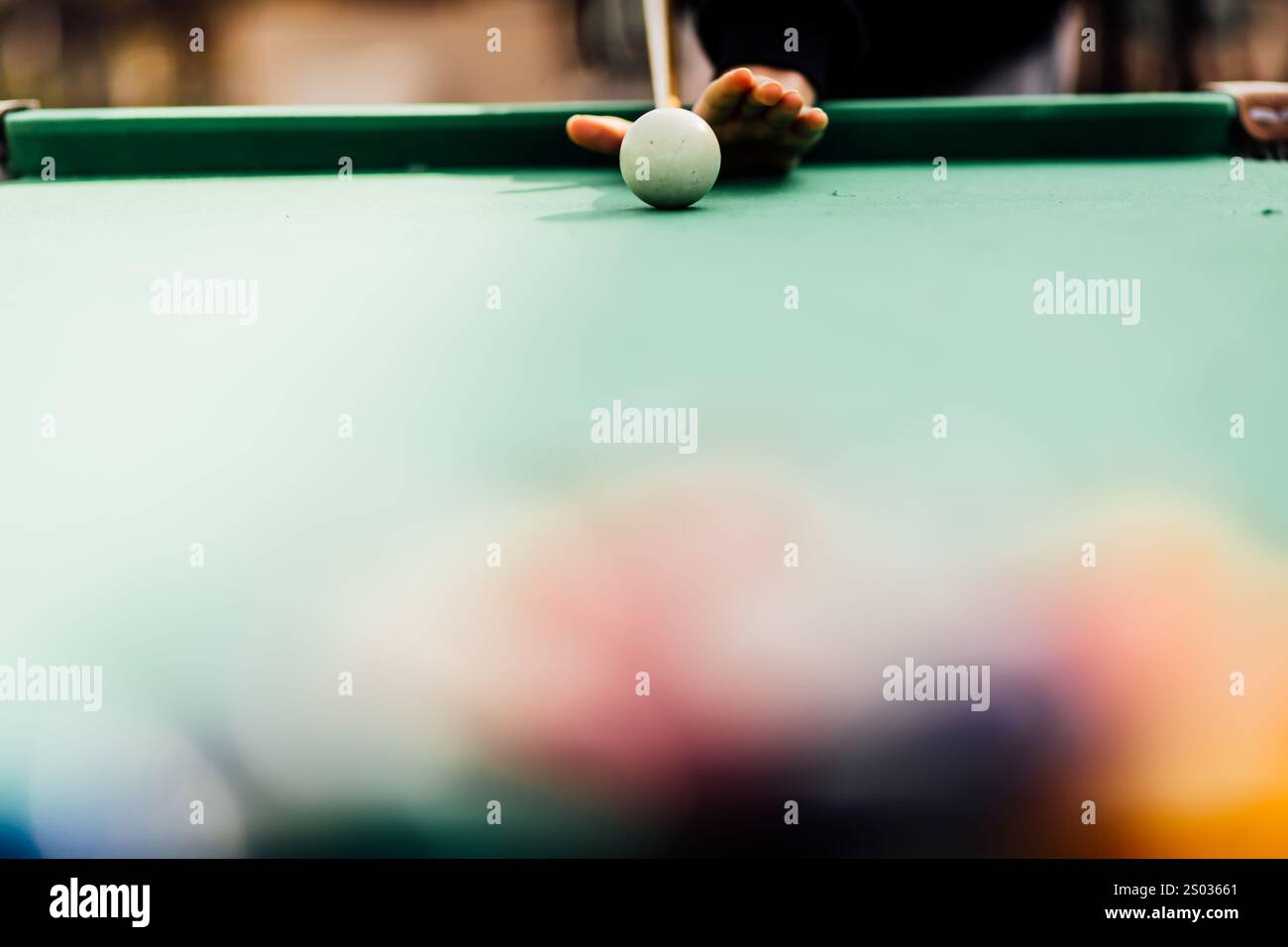 A pool table with scattered billiard balls, a cue stick, and ...