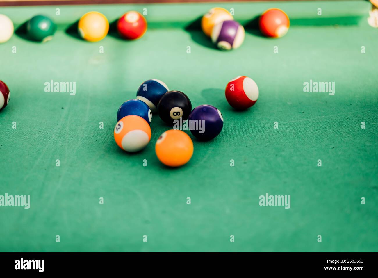 A pool table with scattered billiard balls, a cue stick, and ...