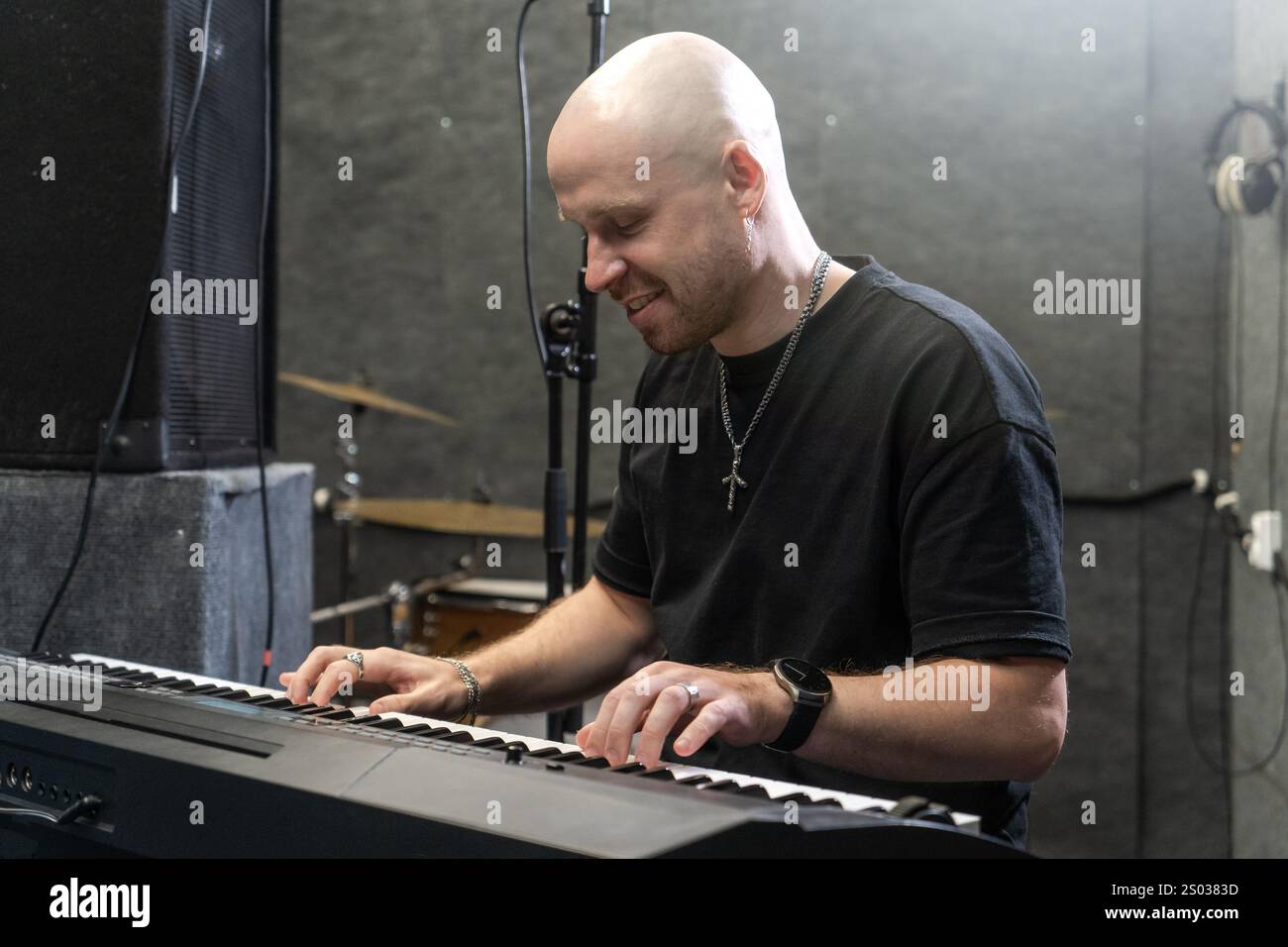 Sound producer working on new hit in recording studio, playing keyboard ...