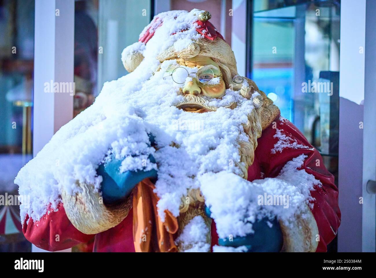 Santa Claus figure covered by snow and snow plows try to combat the ...