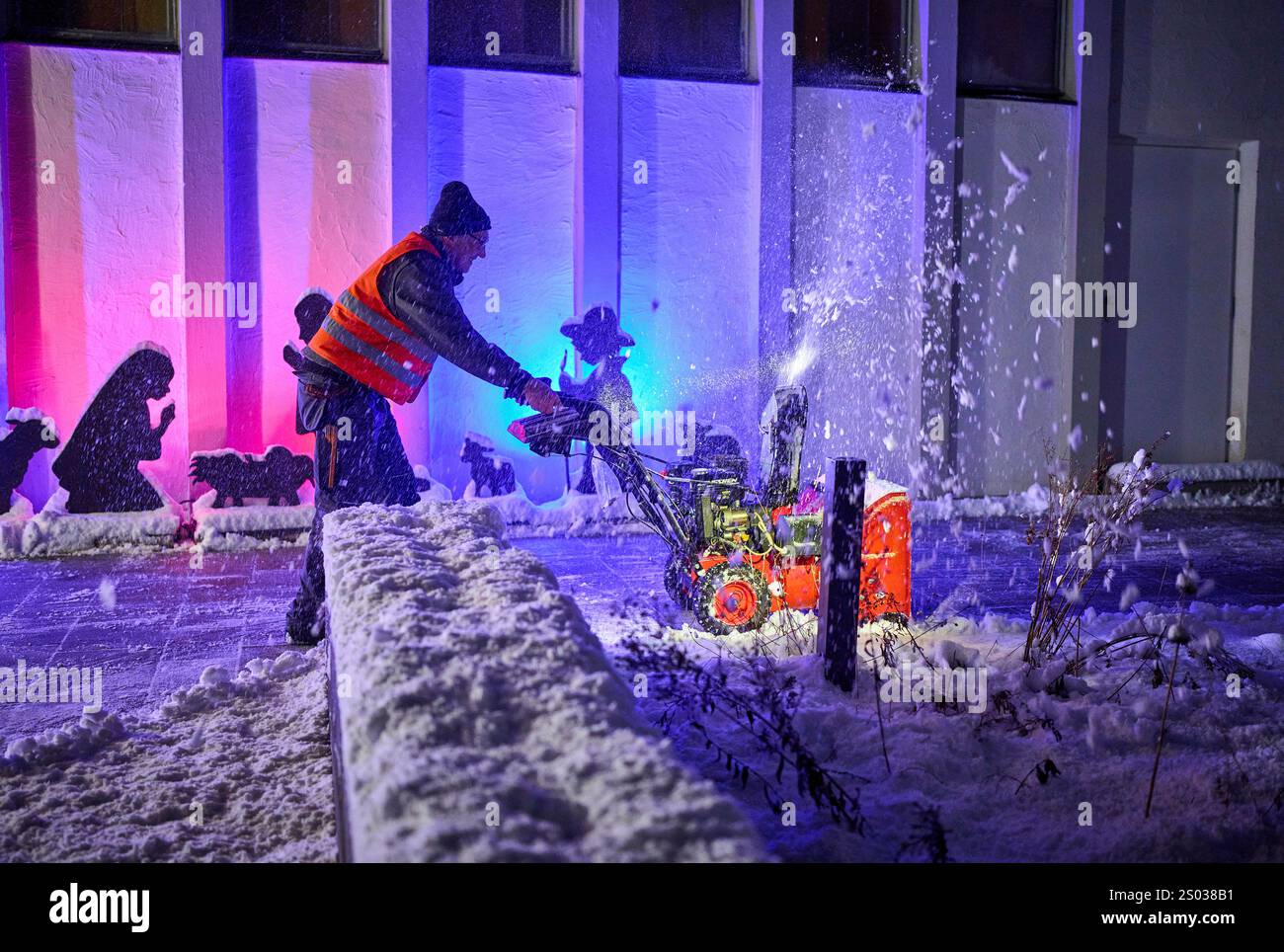 Man with a snow blower in front of a church with Maria and Joseph in ...