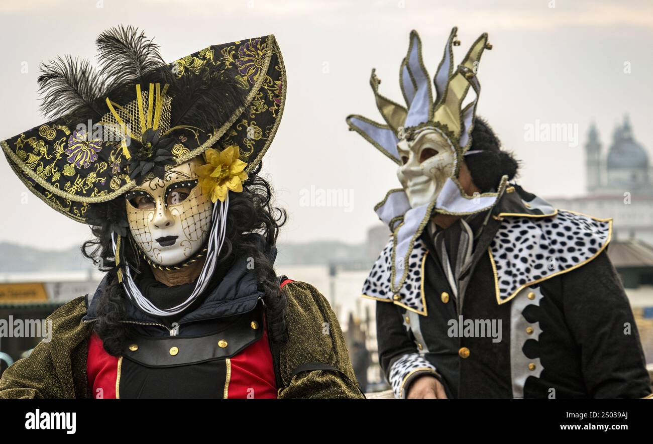Two individuals wearing elaborate masks and costumes during a festival ...