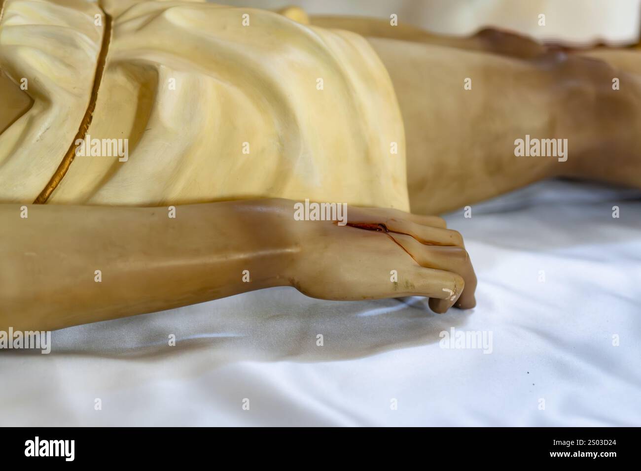 A statue of a man with a hand cut off. The statue is on a white surface ...