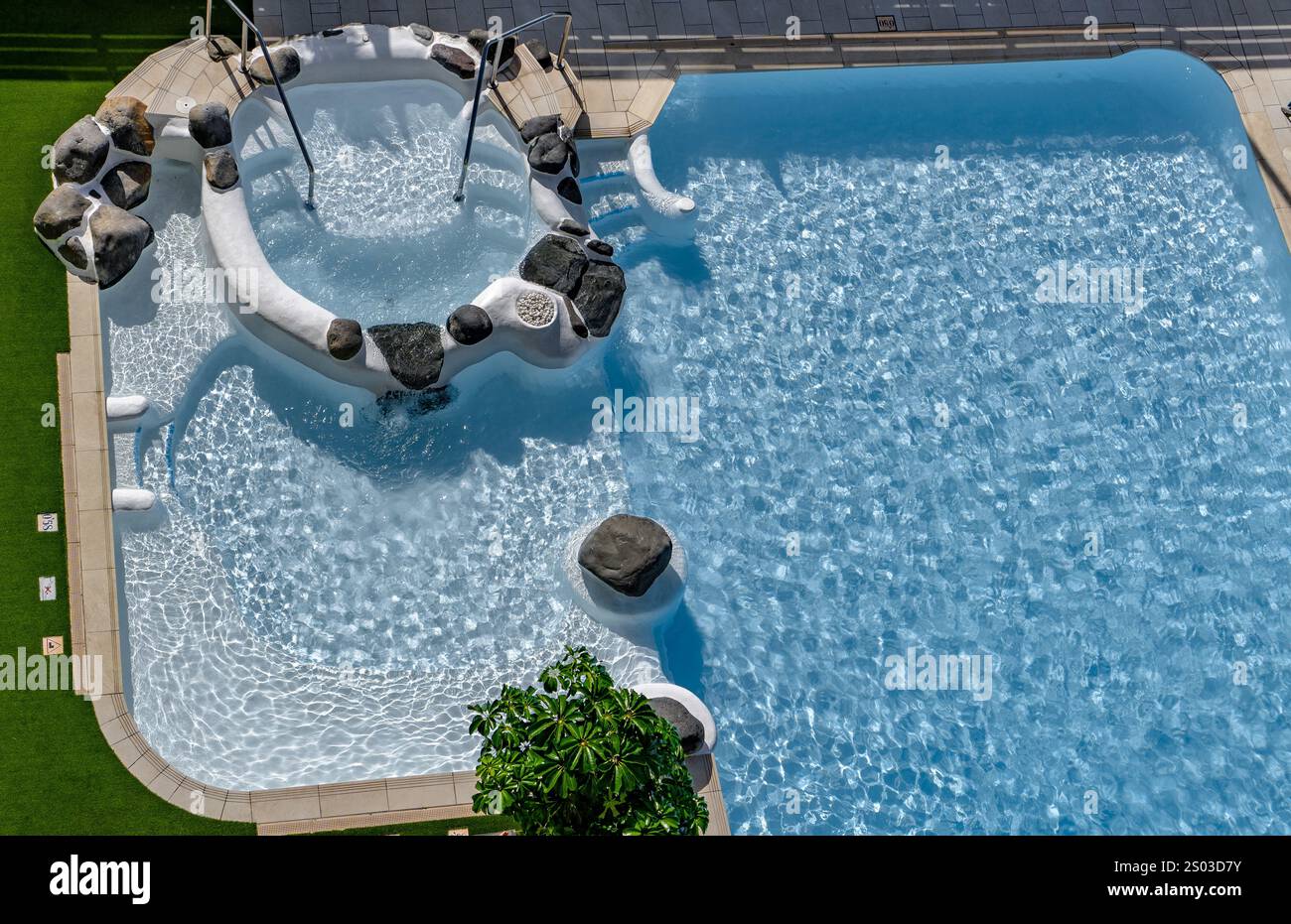 A pool with a small waterfall and a rock ledge. The pool is surrounded ...