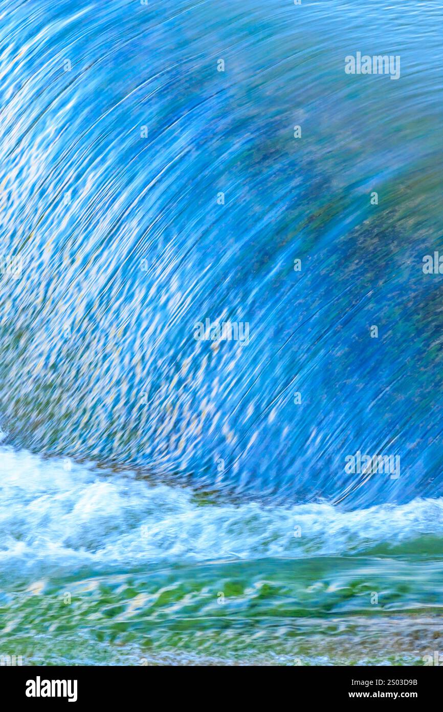 A large wave crashing into the shore, with the water splashing and ...