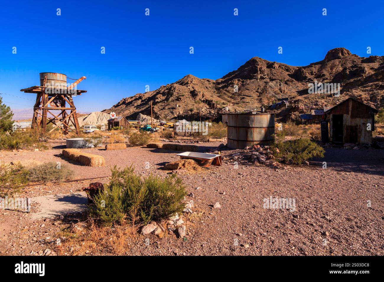 A desert scene with a rusty water tower and a few buildings. The sky is ...