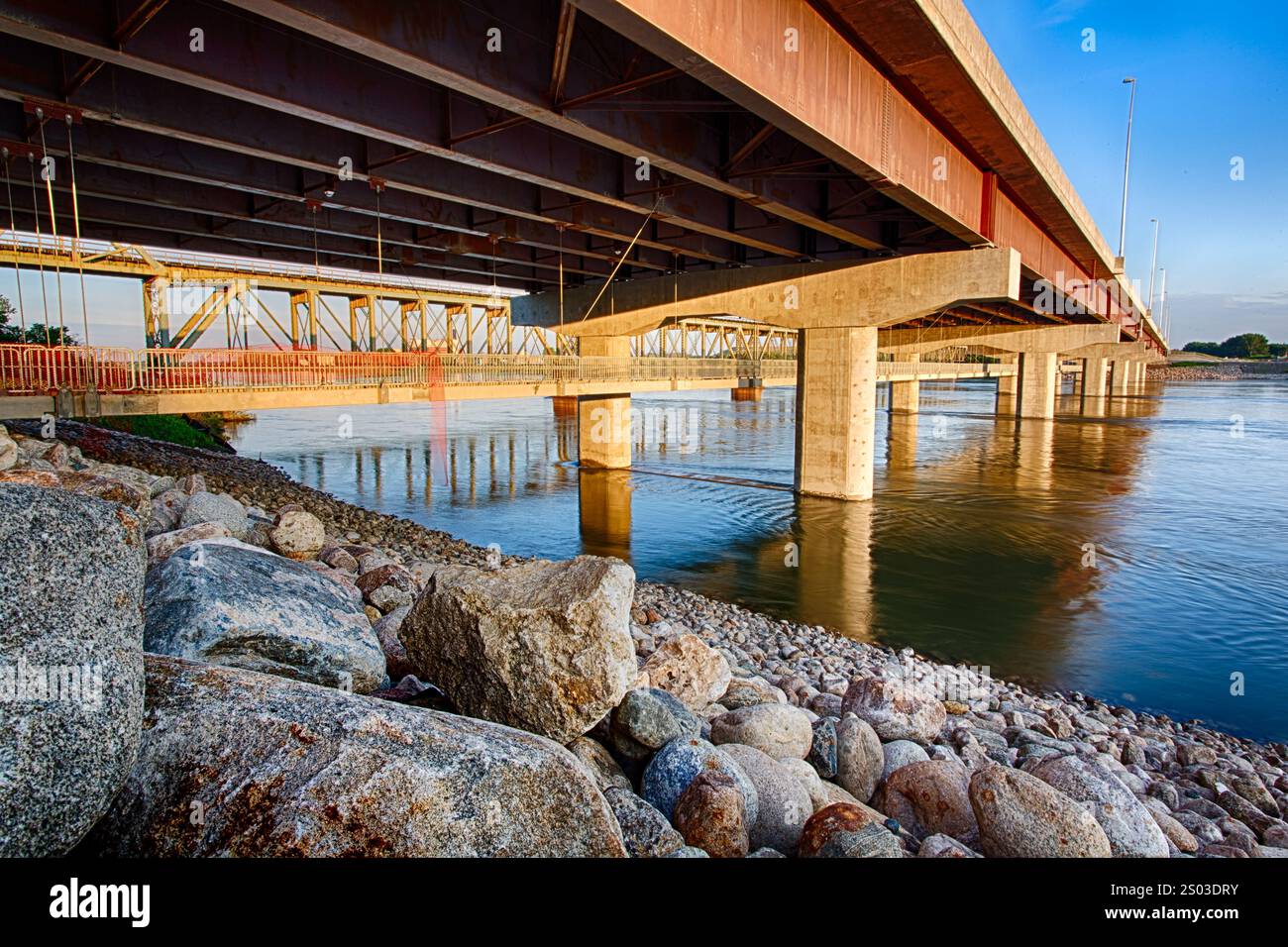 A bridge spans a river with a rocky shoreline. The bridge is a large ...