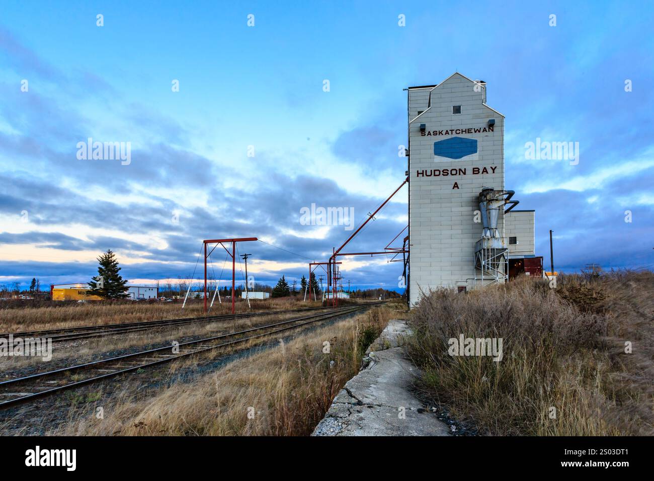 A grain silo in the middle of a field with a cloudy sky in the ...