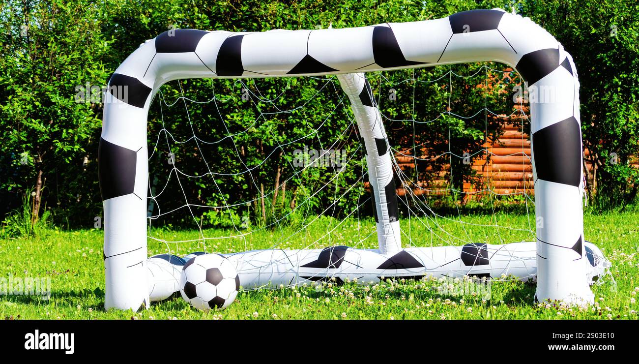 Inflatable soccer goal with a soccer ball design stands on a lush green ...