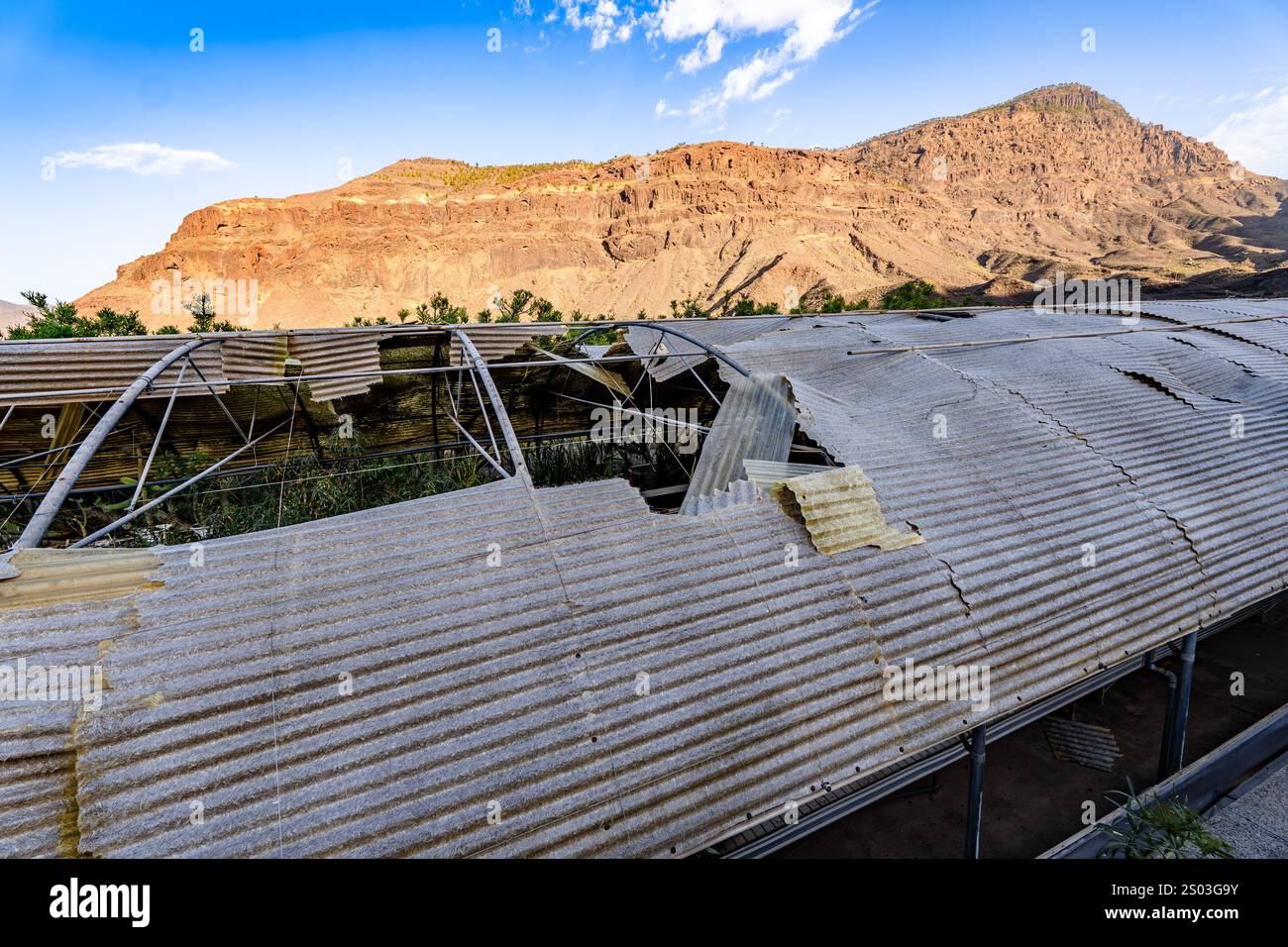 A rusted metal roof with holes in it. The roof is on a building that is ...