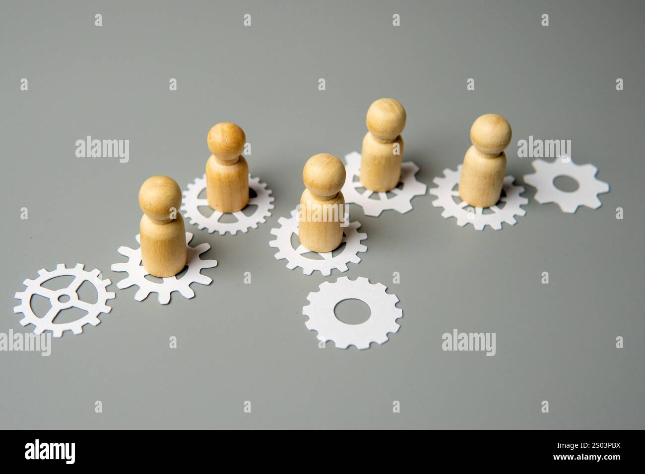 A conceptual image with wooden figures standing on interconnected gears ...