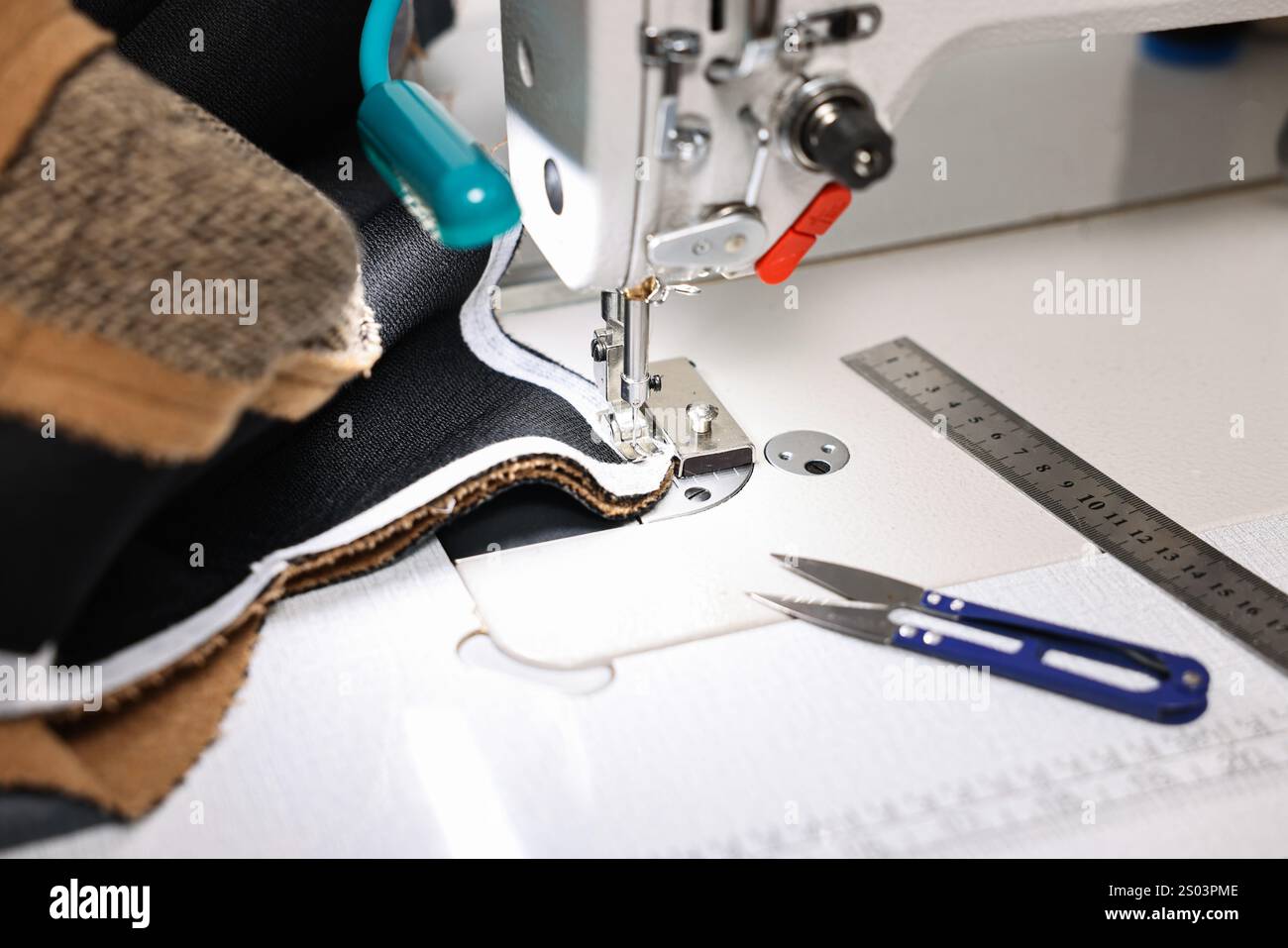 Sewing machine and other tools on white table in professional workshop ...