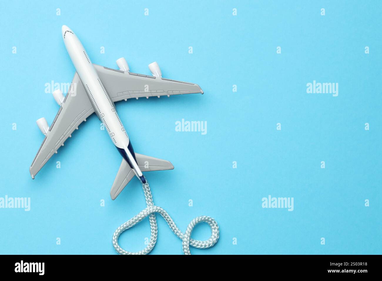 Plane model and rope as flight path on light blue background, top view ...