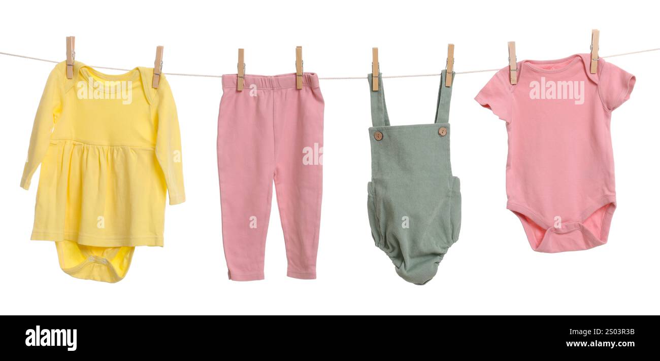 Different baby clothes drying on laundry line against white background ...