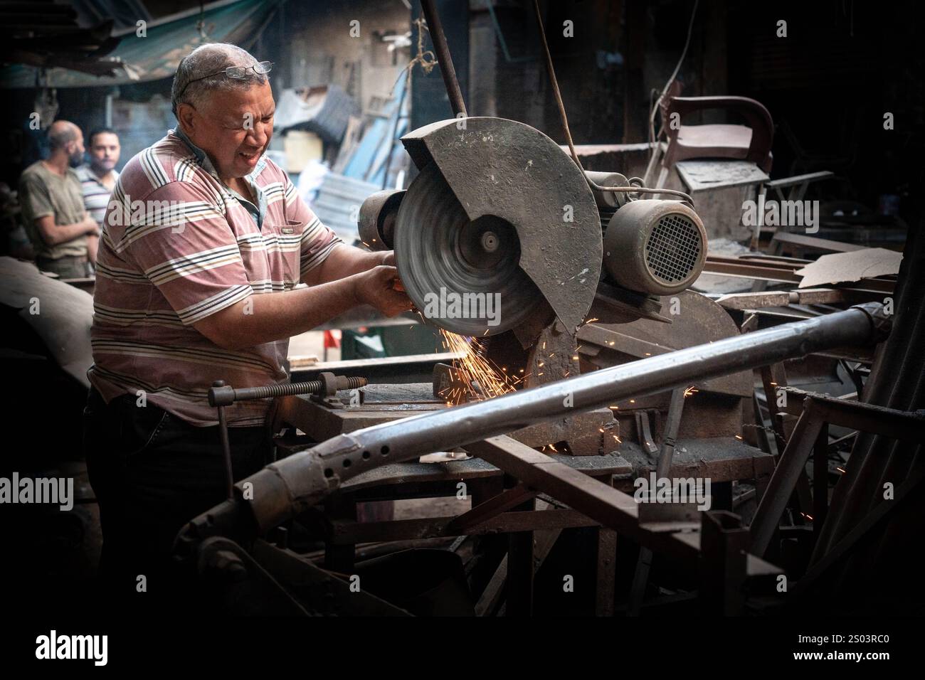 A craftsman works with a cutting tool in an outdoor workshop in Alexandria, Egypt, creating ...