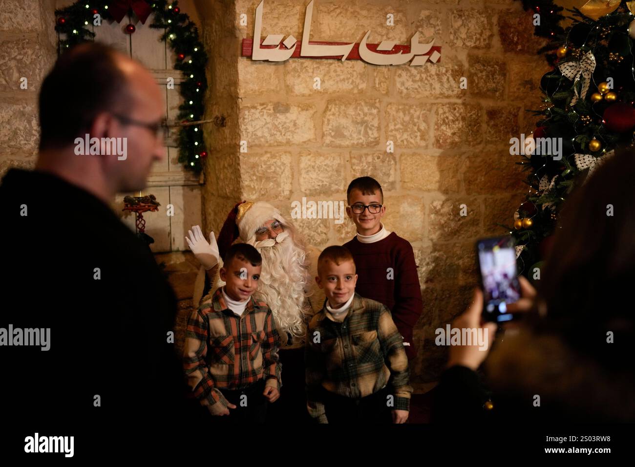 Children pose for a photo with a man dressed as Santa Claus near the ...
