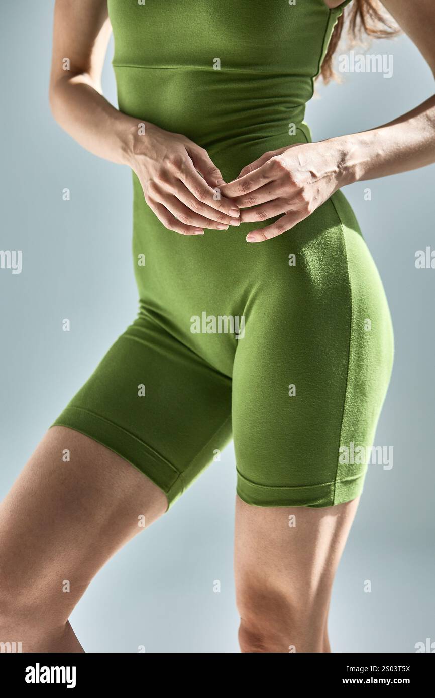 Sporty female wearing green workout clothing with hands near abdomen in ...