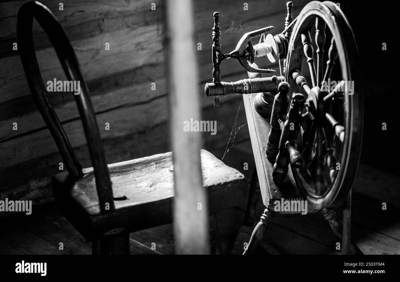 A vintage spinning wheel beside an old wooden chair, set in a rustic ...