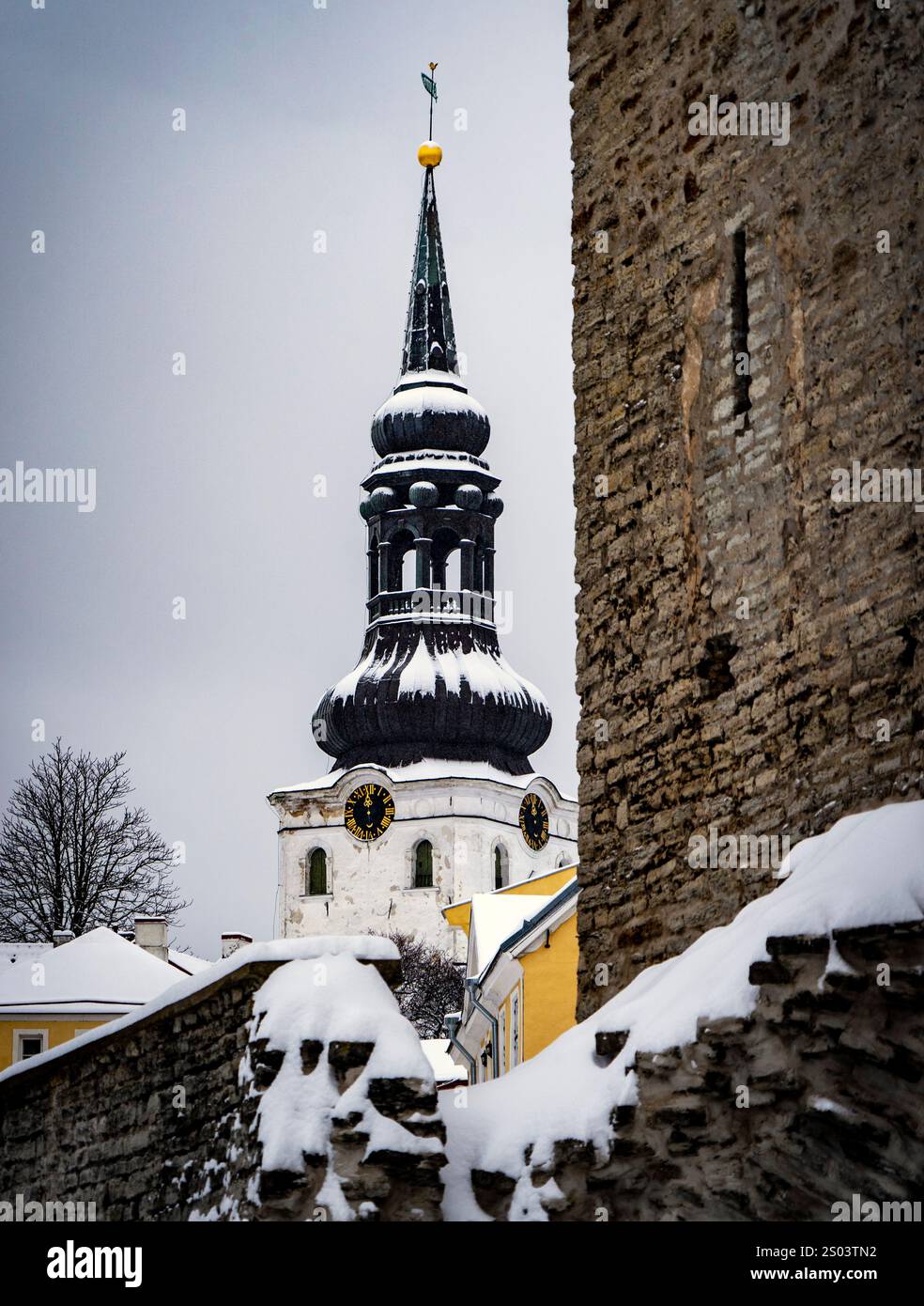 A snow-covered scene featuring a historic church tower with a ...