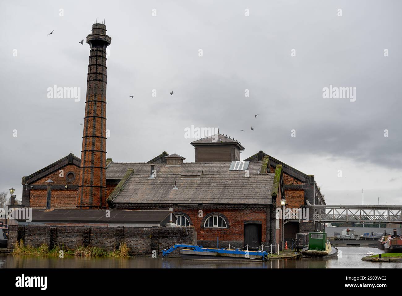 Historic factory warehouse brick building with tall chimney by a canal ...