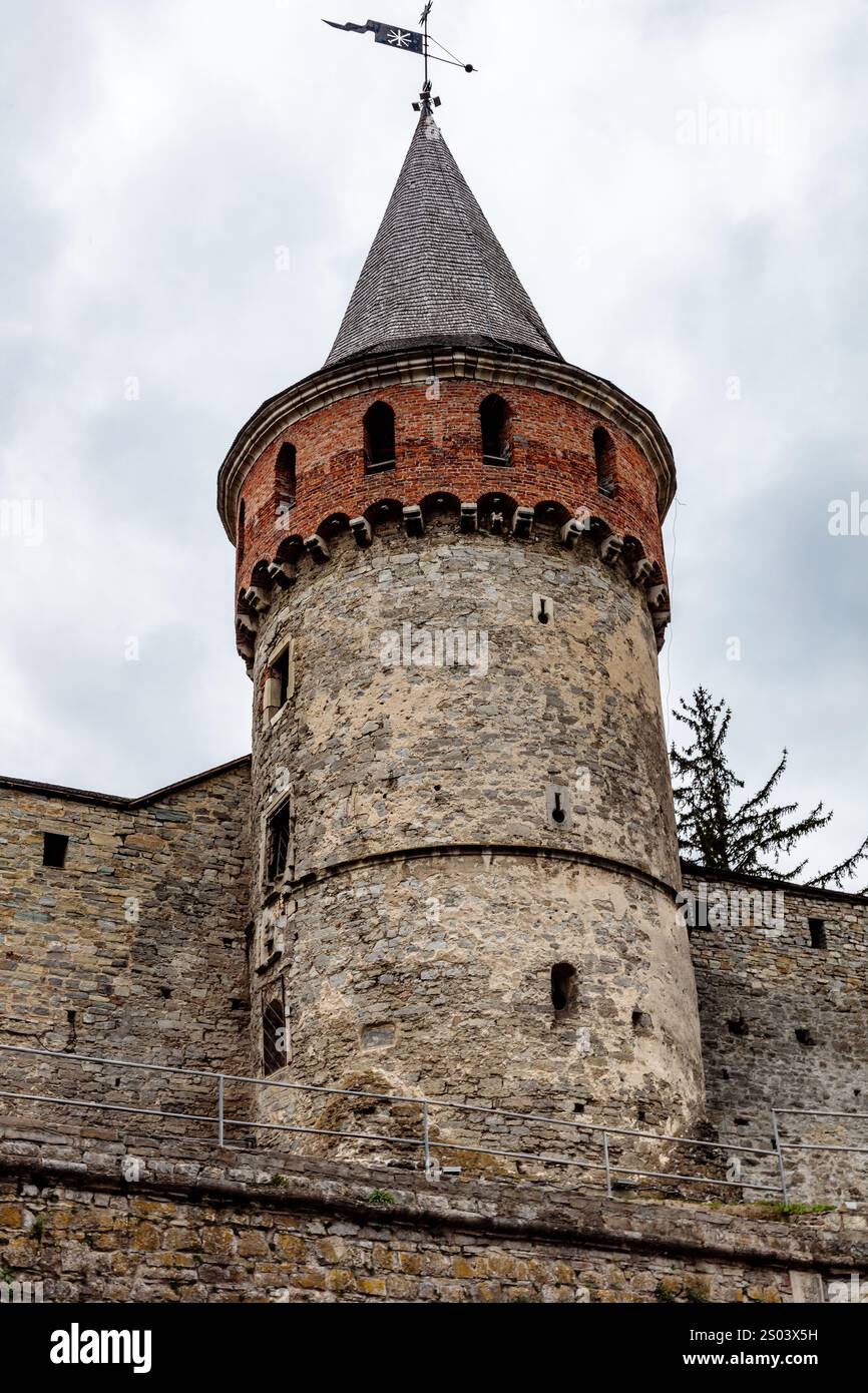 A tall brick tower with a pointed roof. The tower is covered in red ...
