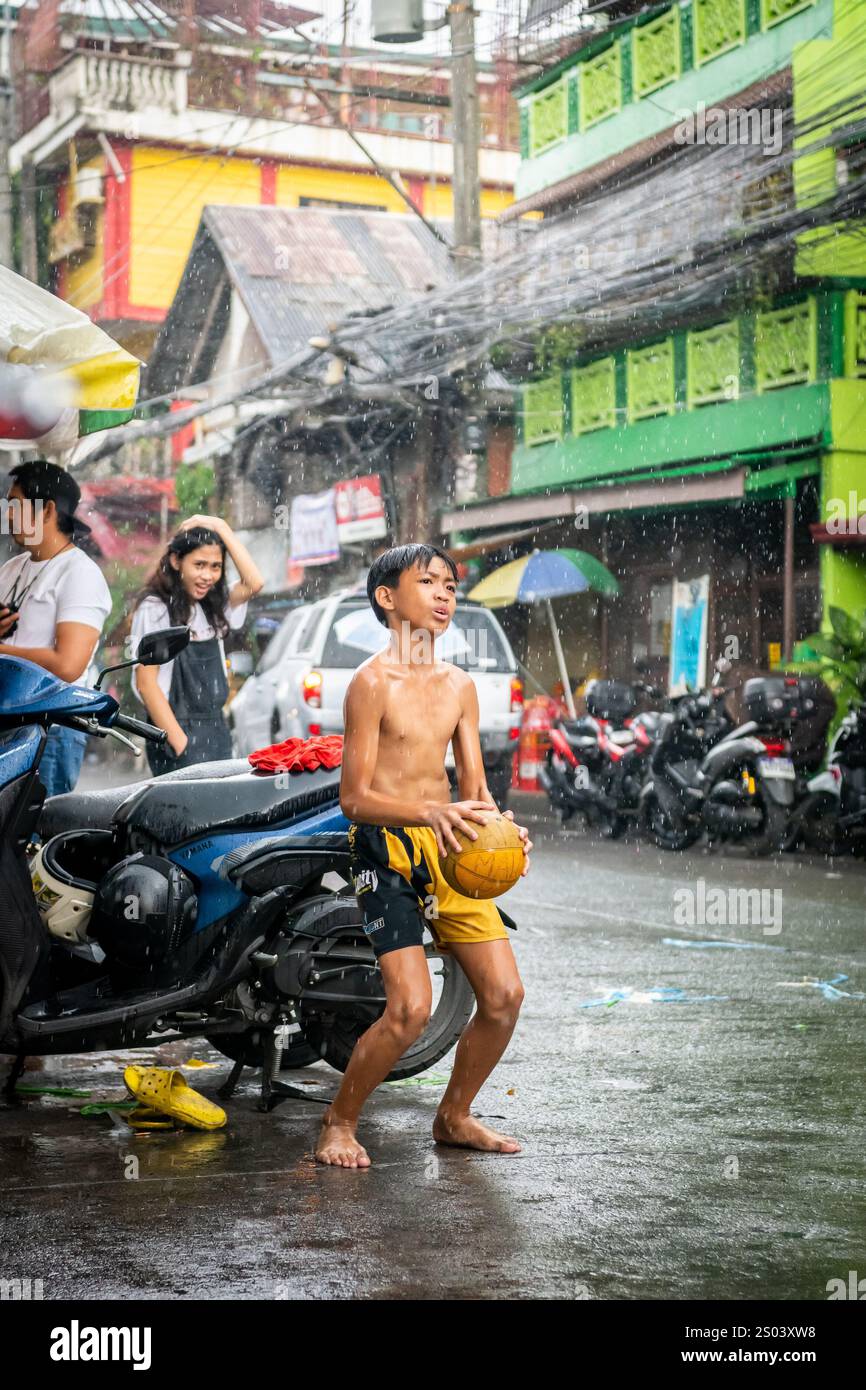 Young Filipino boys play basketball during a rain storm on Asuncion St ...