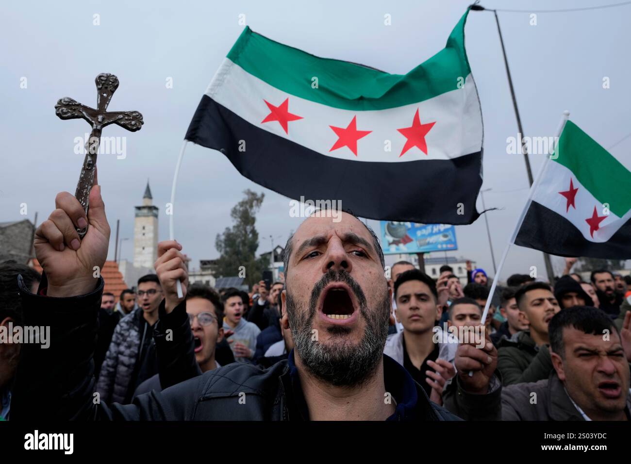 A Syrian Christian man holds up a cross and shouts slogans in Damascus ...