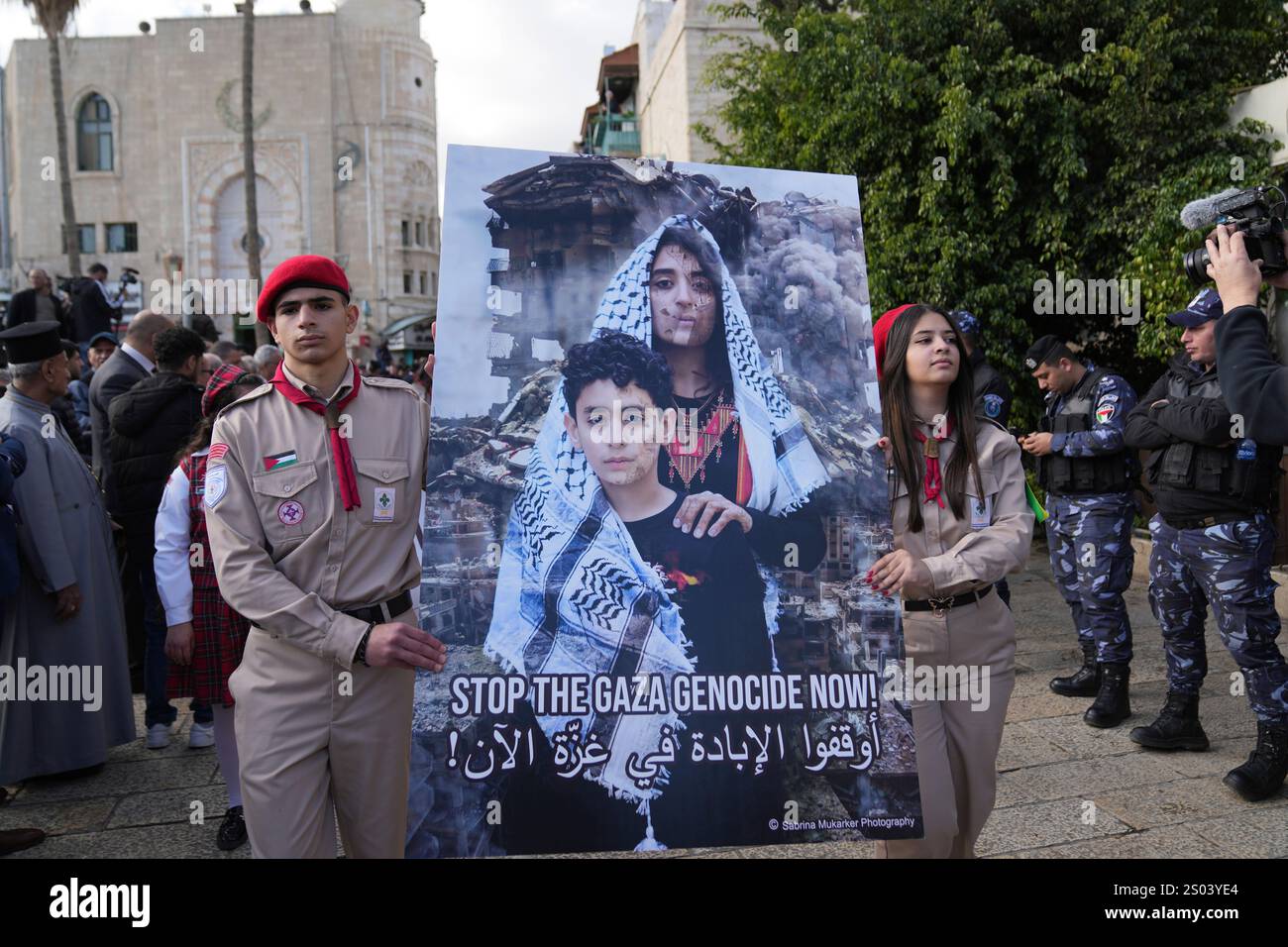 Palestinian scouts carry a poster while they march during Christmas Eve ...