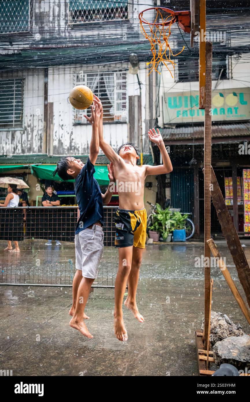 Young Filipino boys play basketball during a rain storm on Asuncion St ...