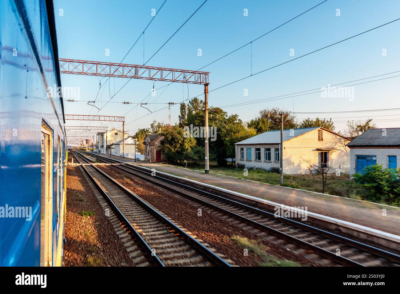 A train is traveling down the tracks with a blue and white train car ...