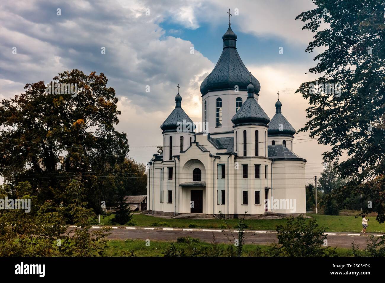 A large white church with a steeple and a cross on top. The church is ...