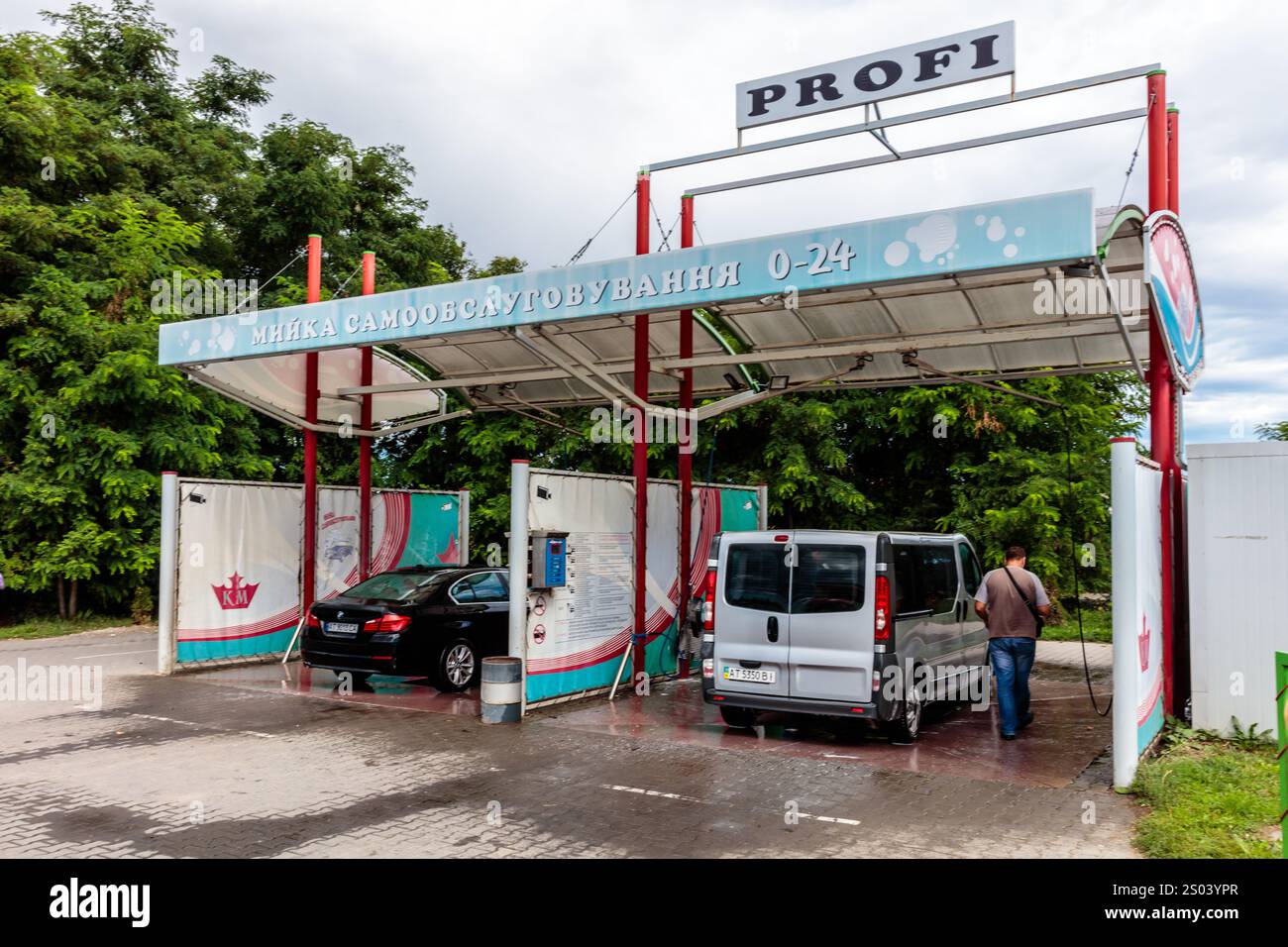 A man is washing his car at a car wash. The car wash is open 24 hours a ...