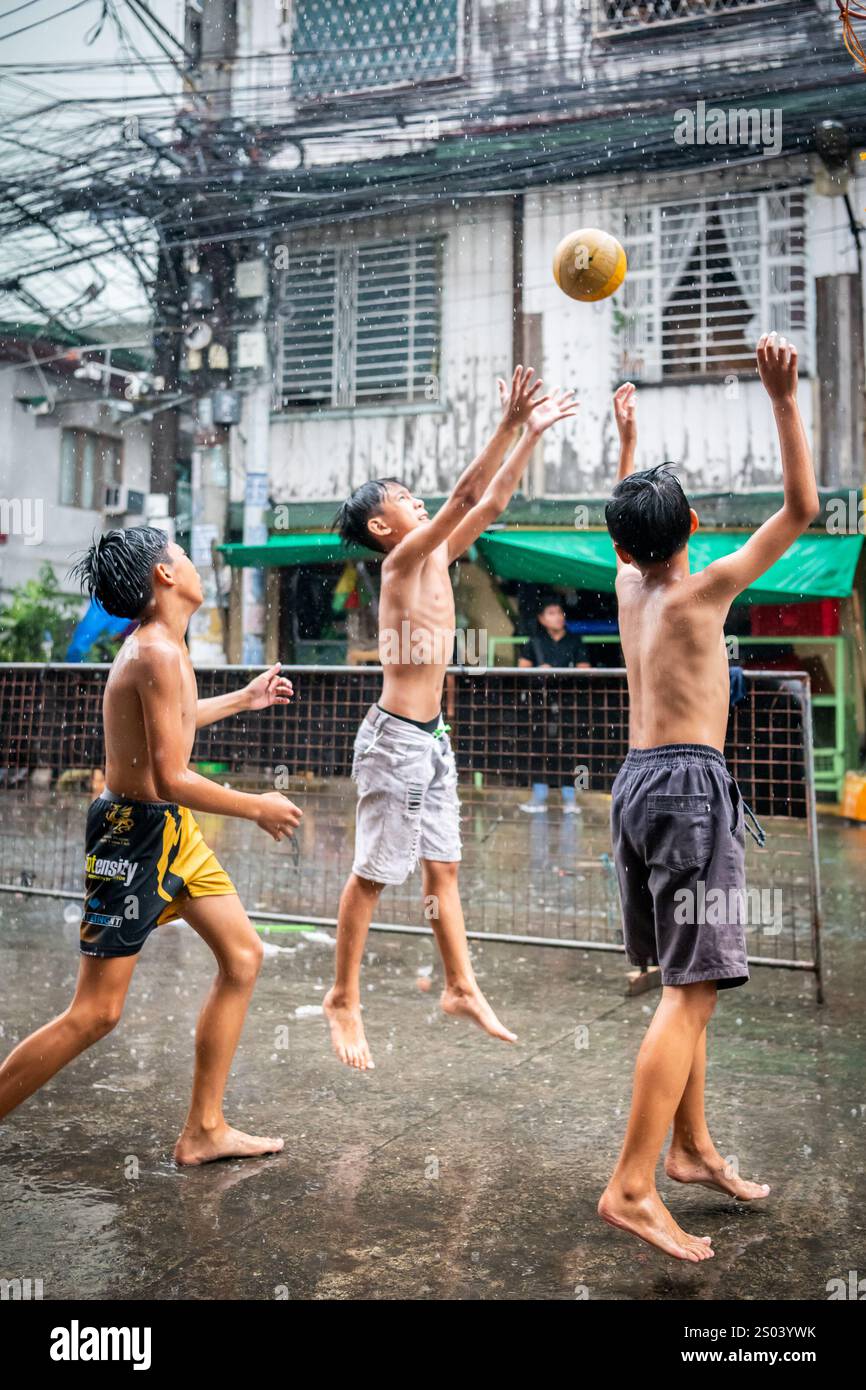 Young Filipino boys play basketball during a rain storm on Asuncion St. Tondo, Manila The ...