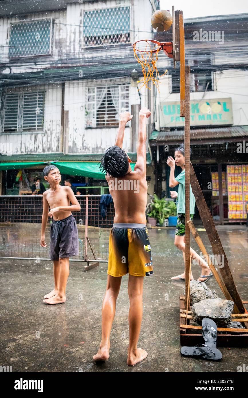 Young Filipino boys play basketball during a rain storm on Asuncion St. Tondo, Manila The ...