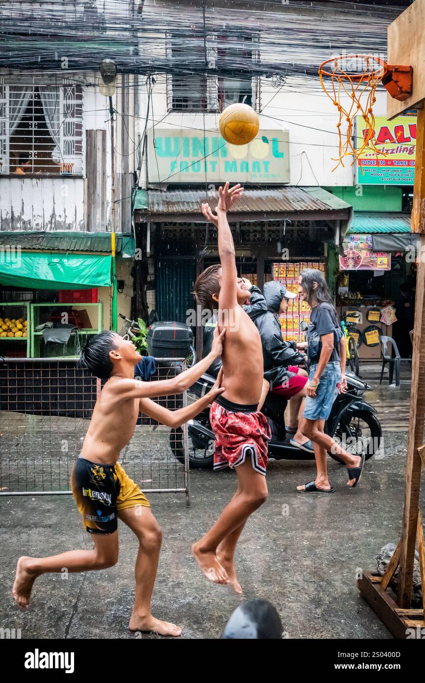 Young Filipino boys play basketball during a rain storm on Asuncion St. Tondo, Manila The ...