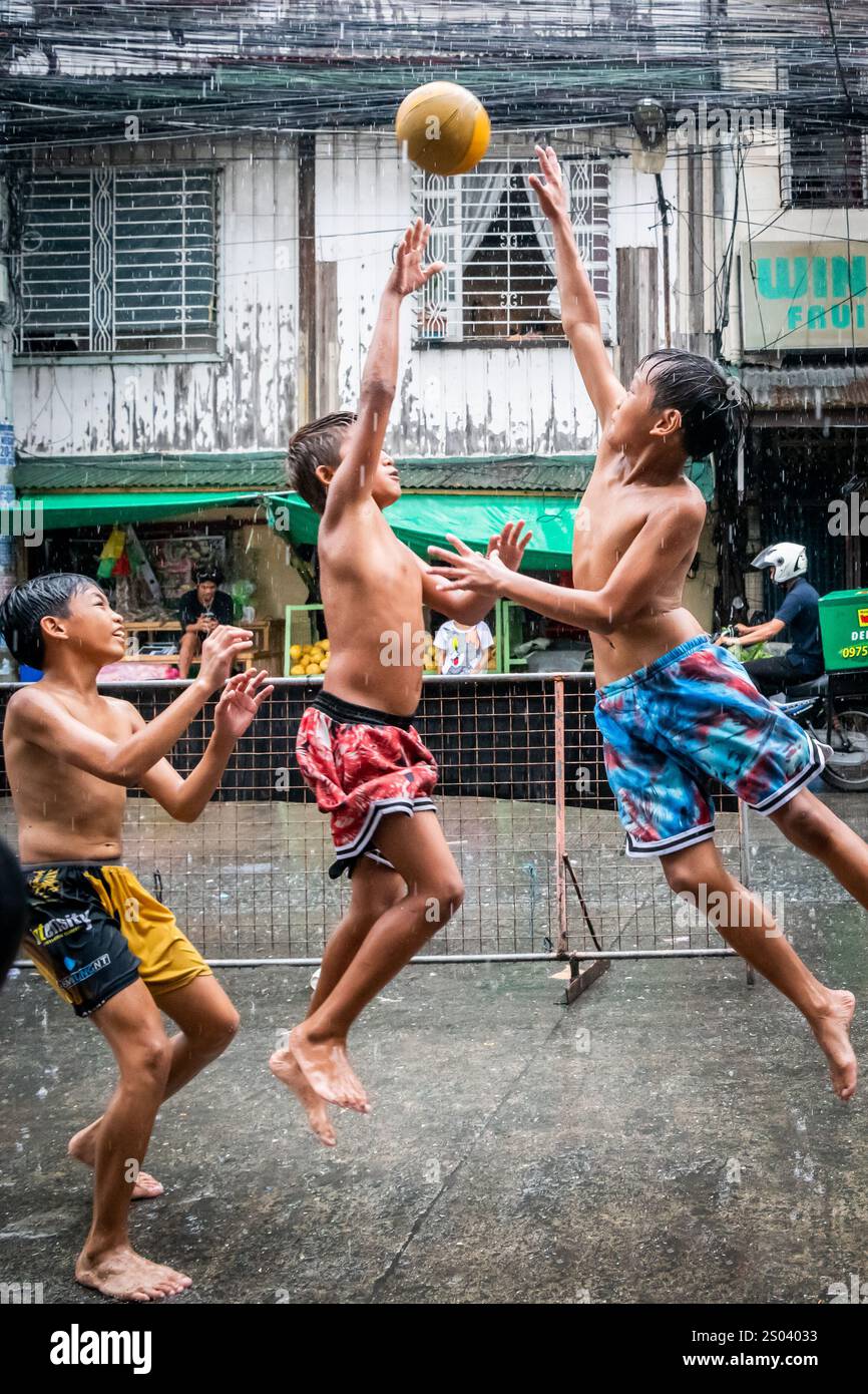 Young Filipino boys play basketball during a rain storm on Asuncion St ...