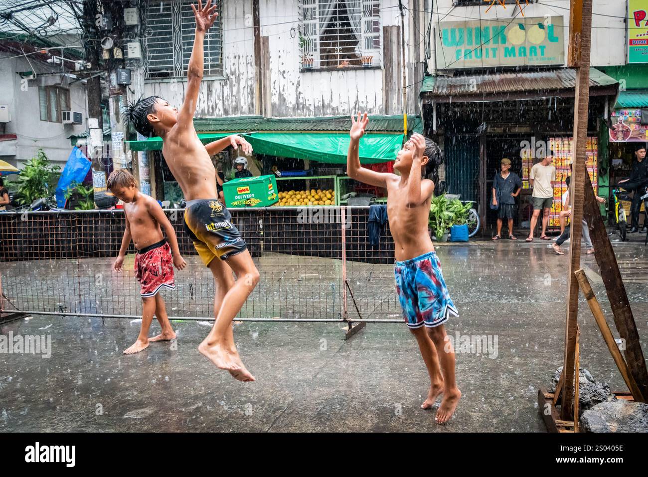Young Filipino boys play basketball during a rain storm on Asuncion St ...