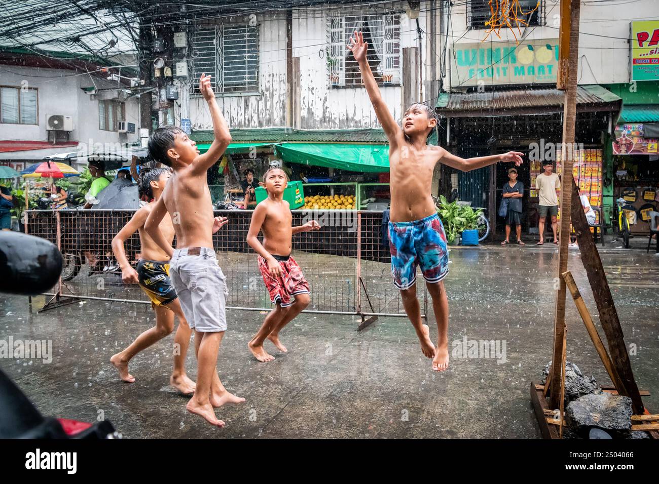 Young Filipino boys play basketball during a rain storm on Asuncion St. Tondo, Manila The ...