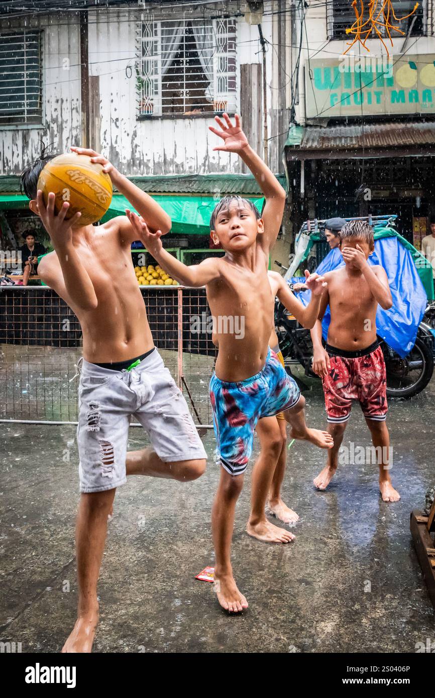 Young Filipino boys play basketball during a rain storm on Asuncion St. Tondo, Manila The ...