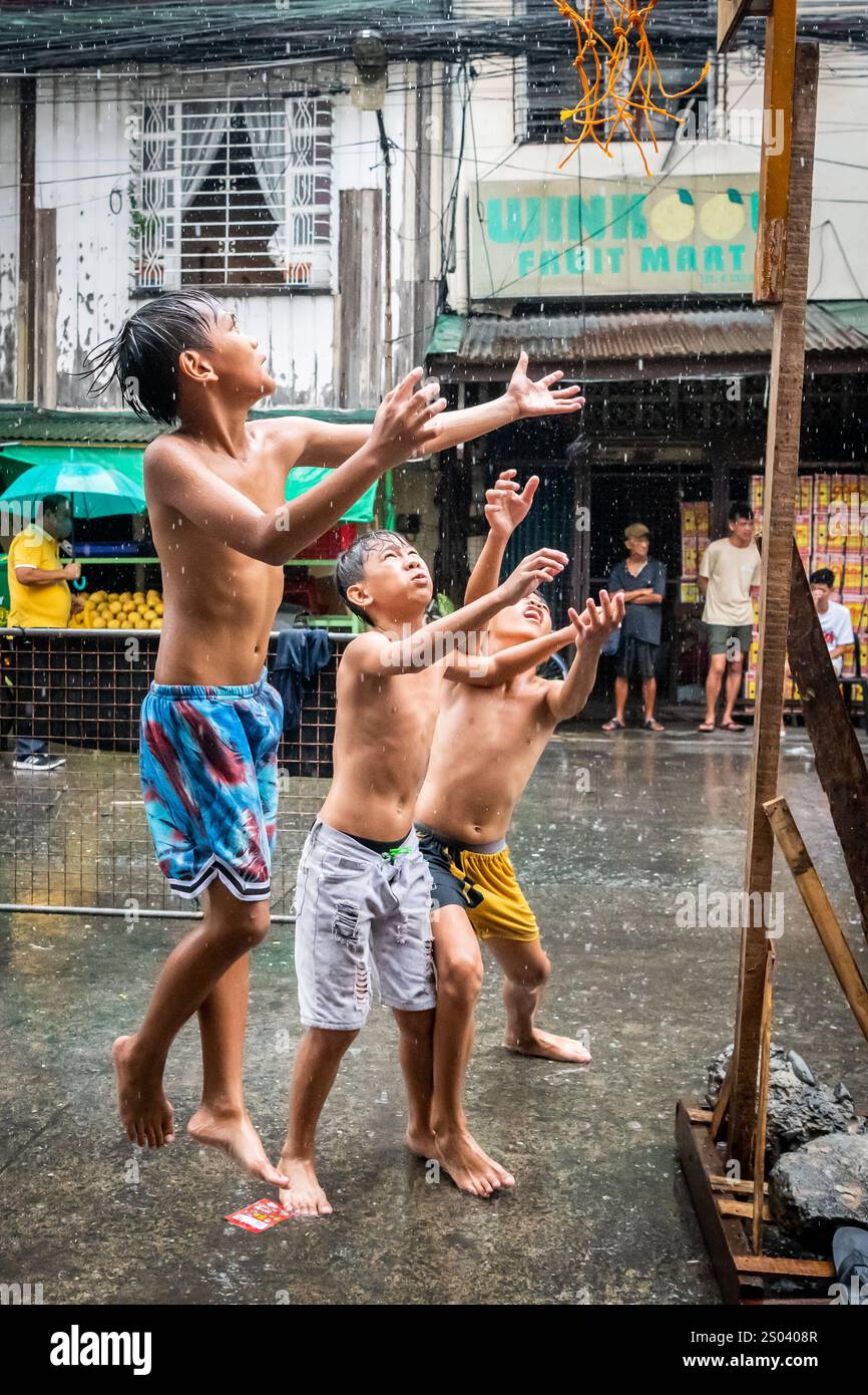 Young Filipino boys play basketball during a rain storm on Asuncion St. Tondo, Manila The ...