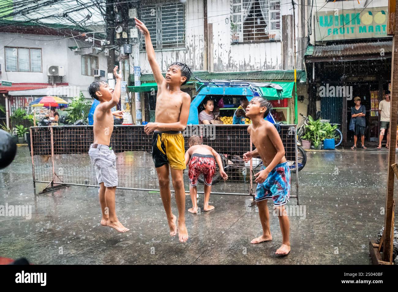 Young Filipino boys play basketball during a rain storm on Asuncion St ...
