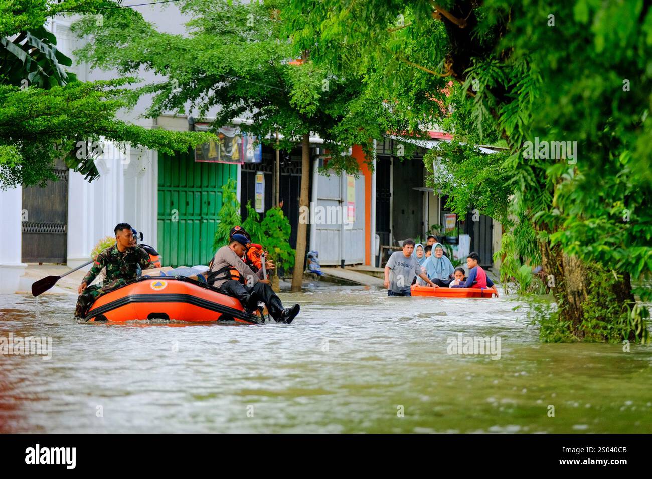 Makassar, Indonesia. 24th Dec, 2024. People ride rubber boats in flood water after heavy rain ...