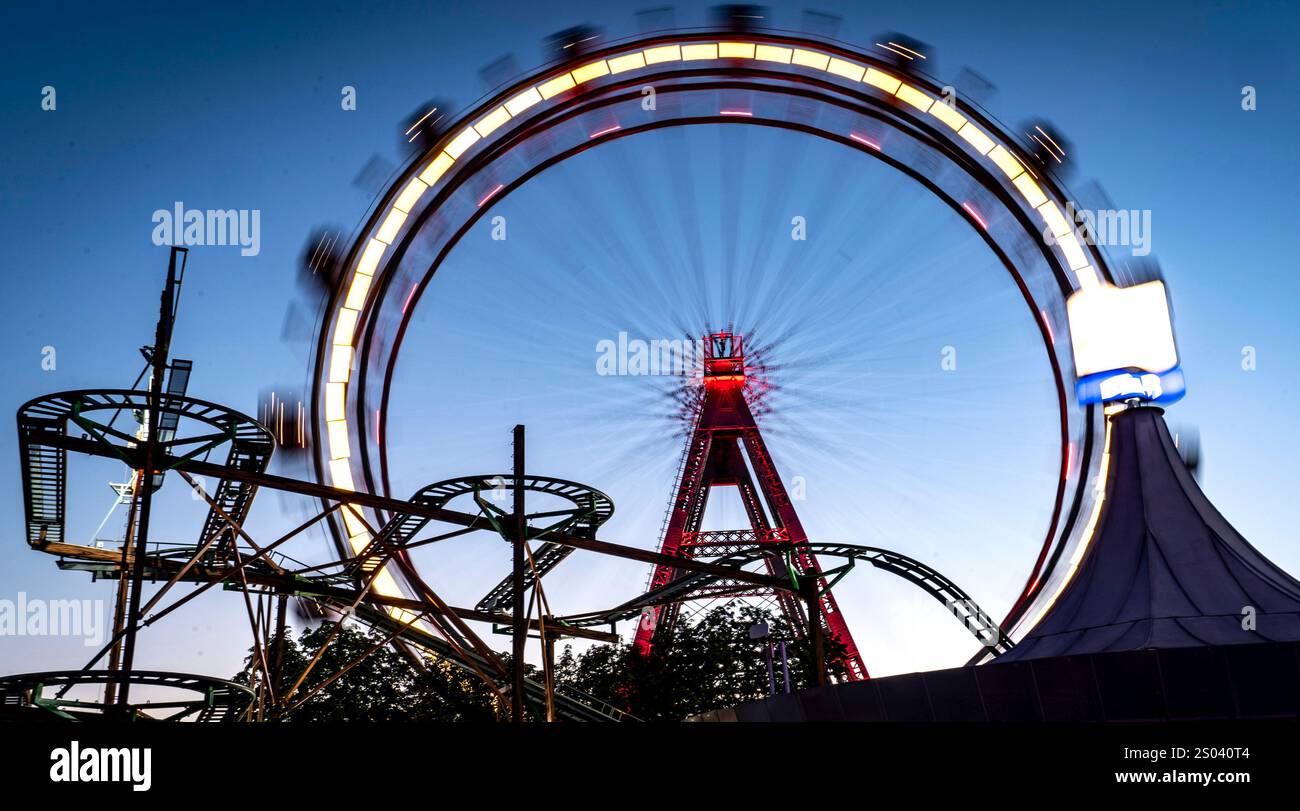 A vibrant amusement park scene featuring a large Ferris wheel illuminated against a twilight sky ...