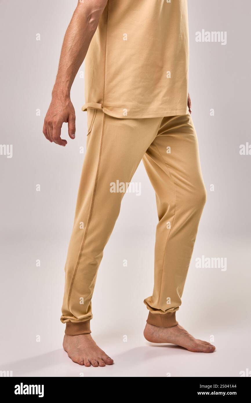 Casual apparel with beige, relaxed-fit sweatpants, barefoot, male model ...