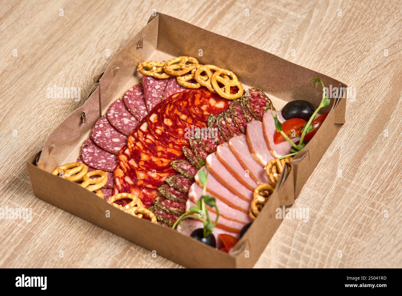 An assortment of sliced salami, chorizo, and ham with pretzels, olives ...